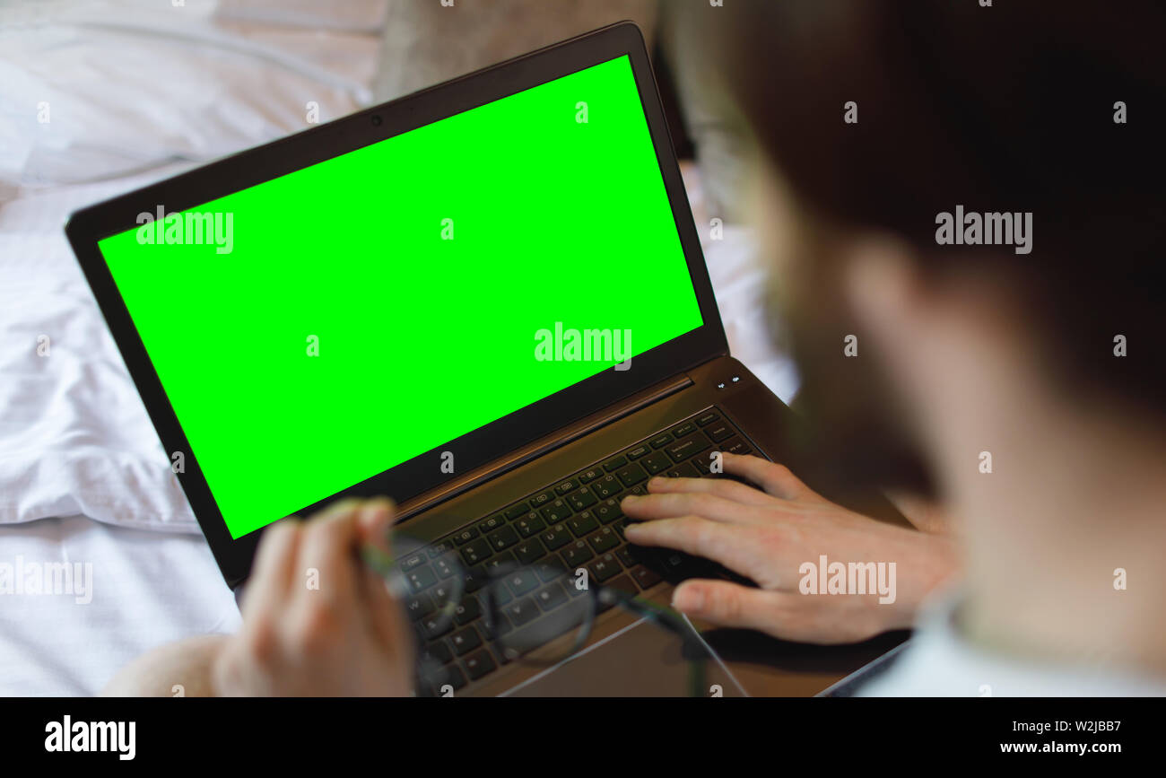Young man working on his laptop computer connected to wireless internet ...