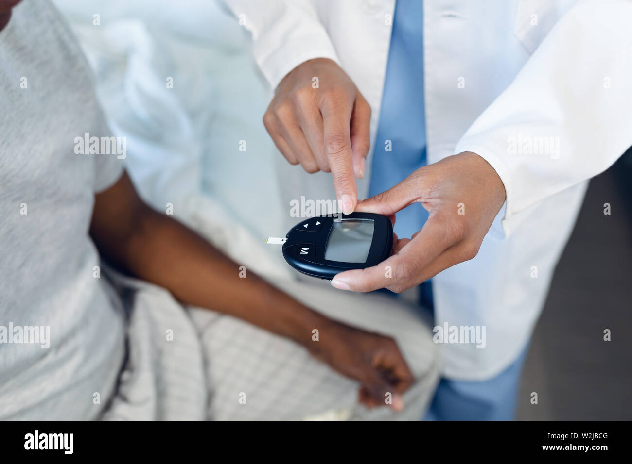 Female doctor taking patients blood sample with lancet pen in the ward ...