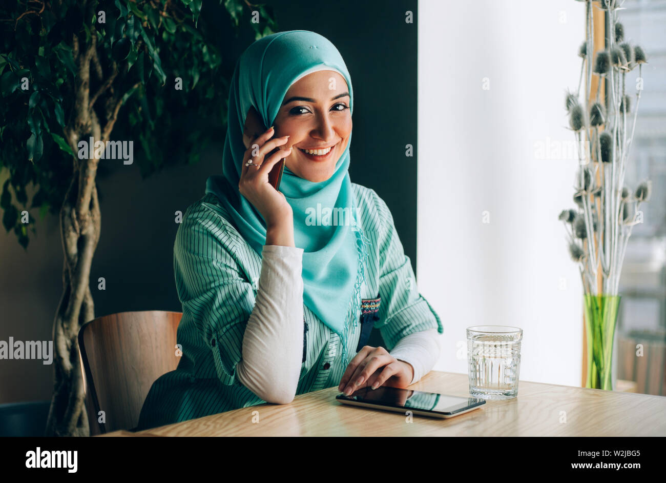 Beautiful young arabic girl in hijab talking by phone at cafe Stock ...