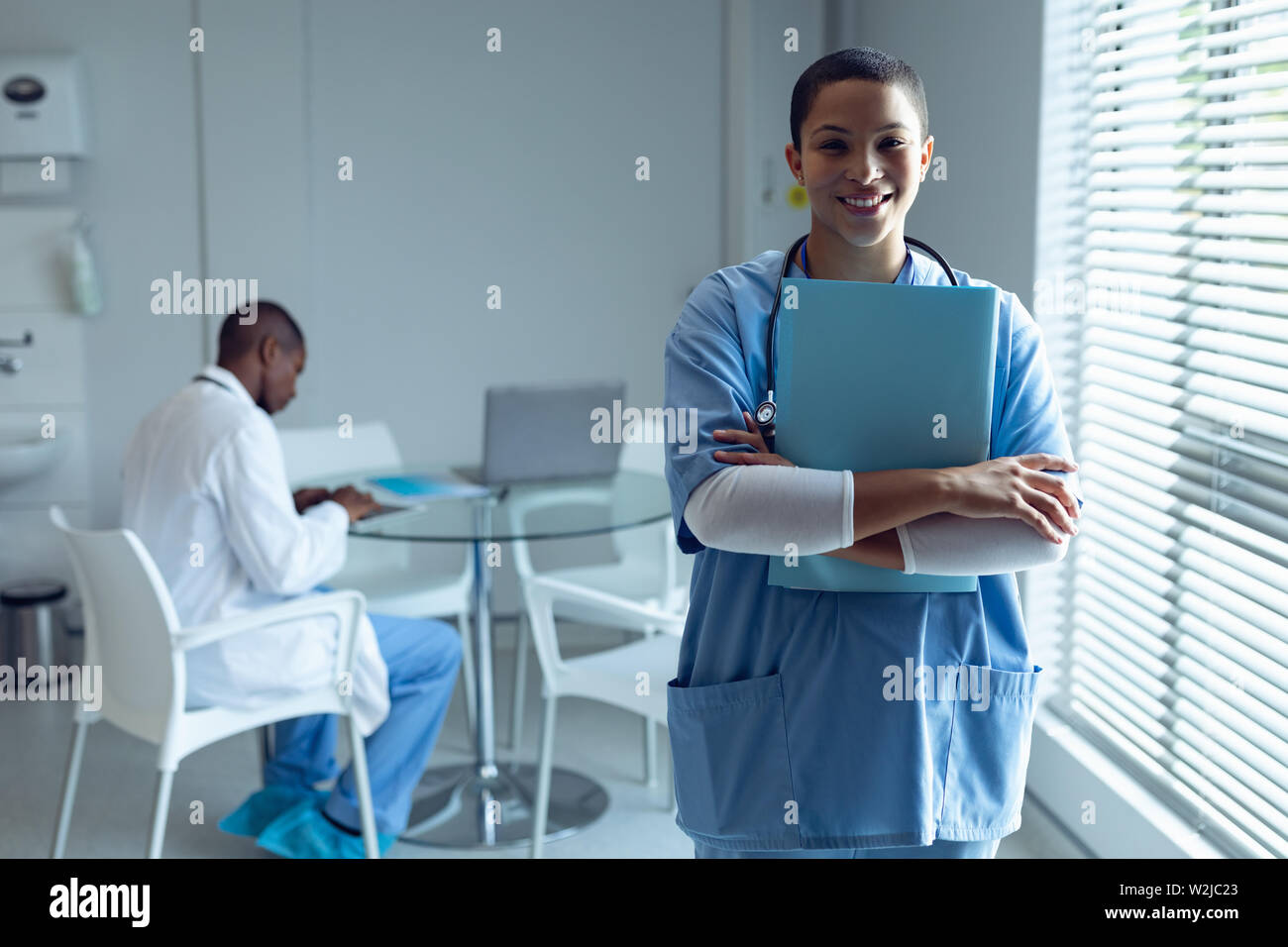 Female doctor holding file and smiling in the hospital Stock Photo - Alamy