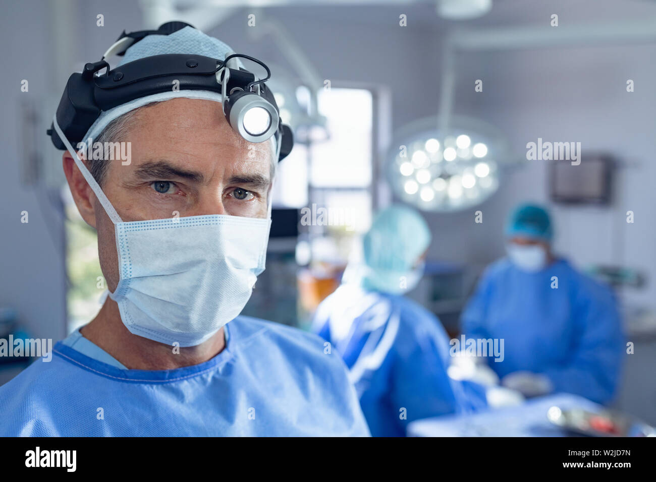 Male surgeon with surgical headlight standing in operation room Stock ...