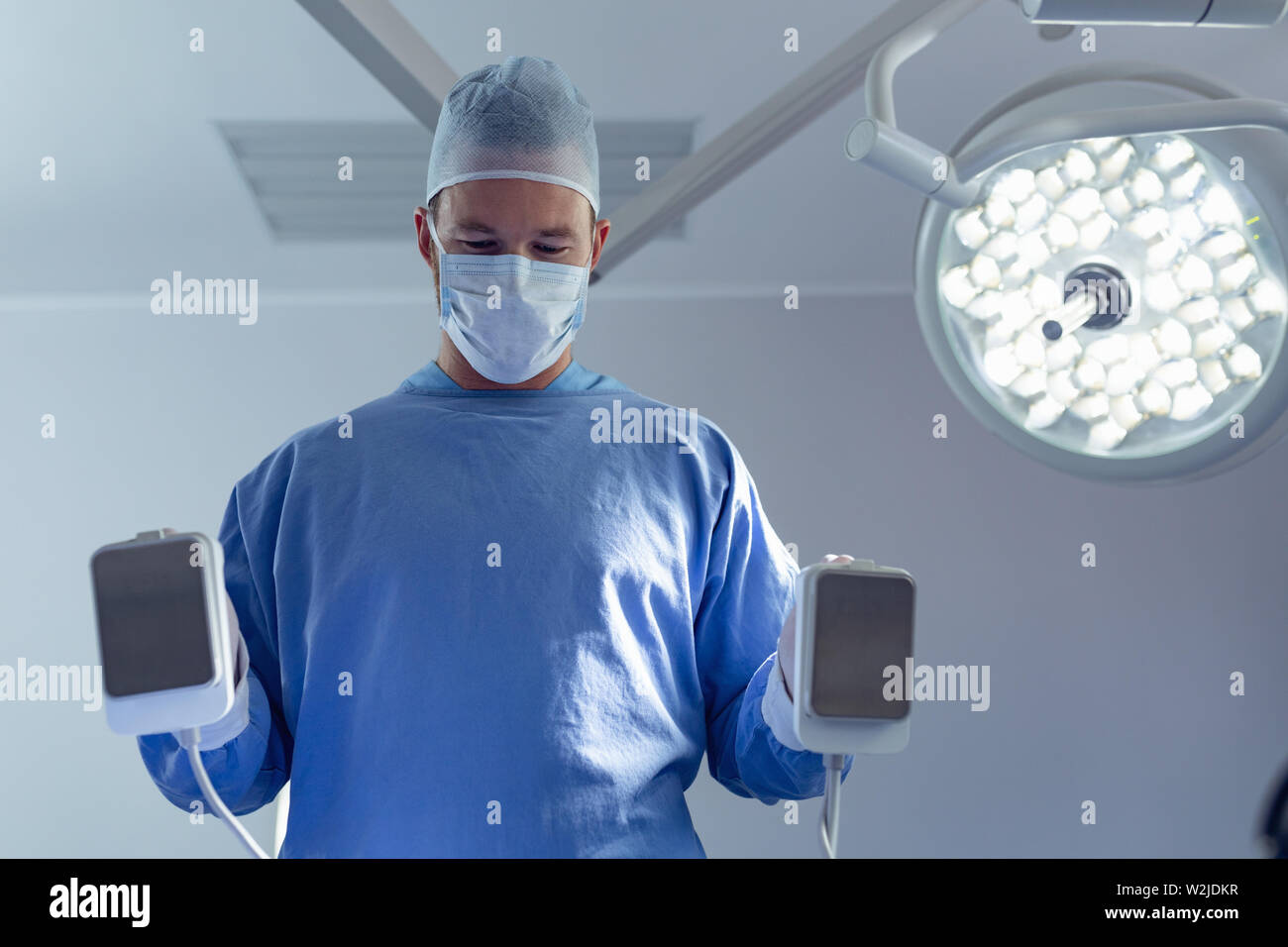 Male surgeon holding defibrillator in operation room at the hospital ...