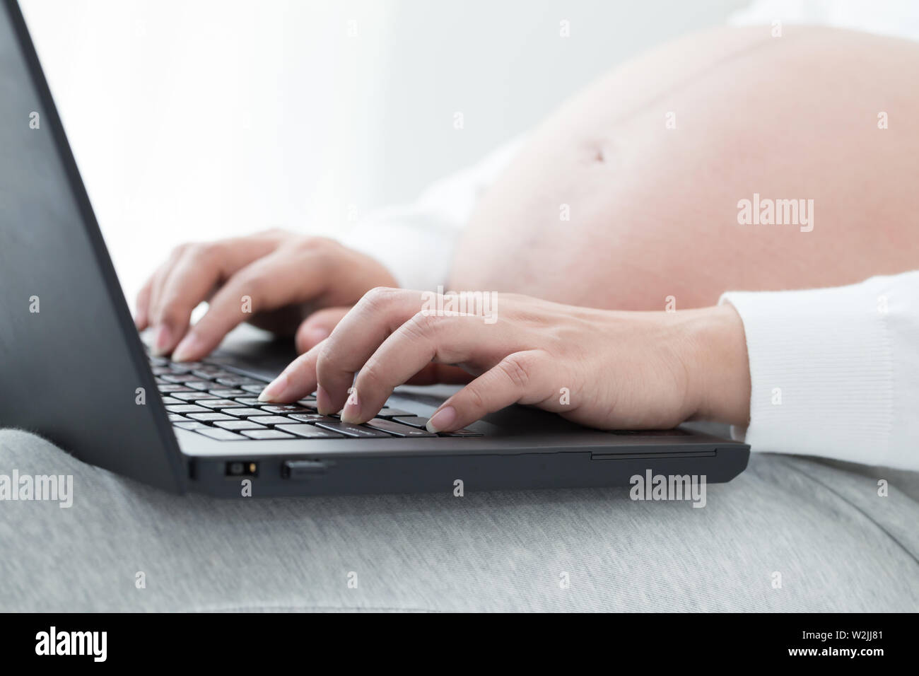 Pregnant women hand typing on keyboard on notebook to searching newborn ...