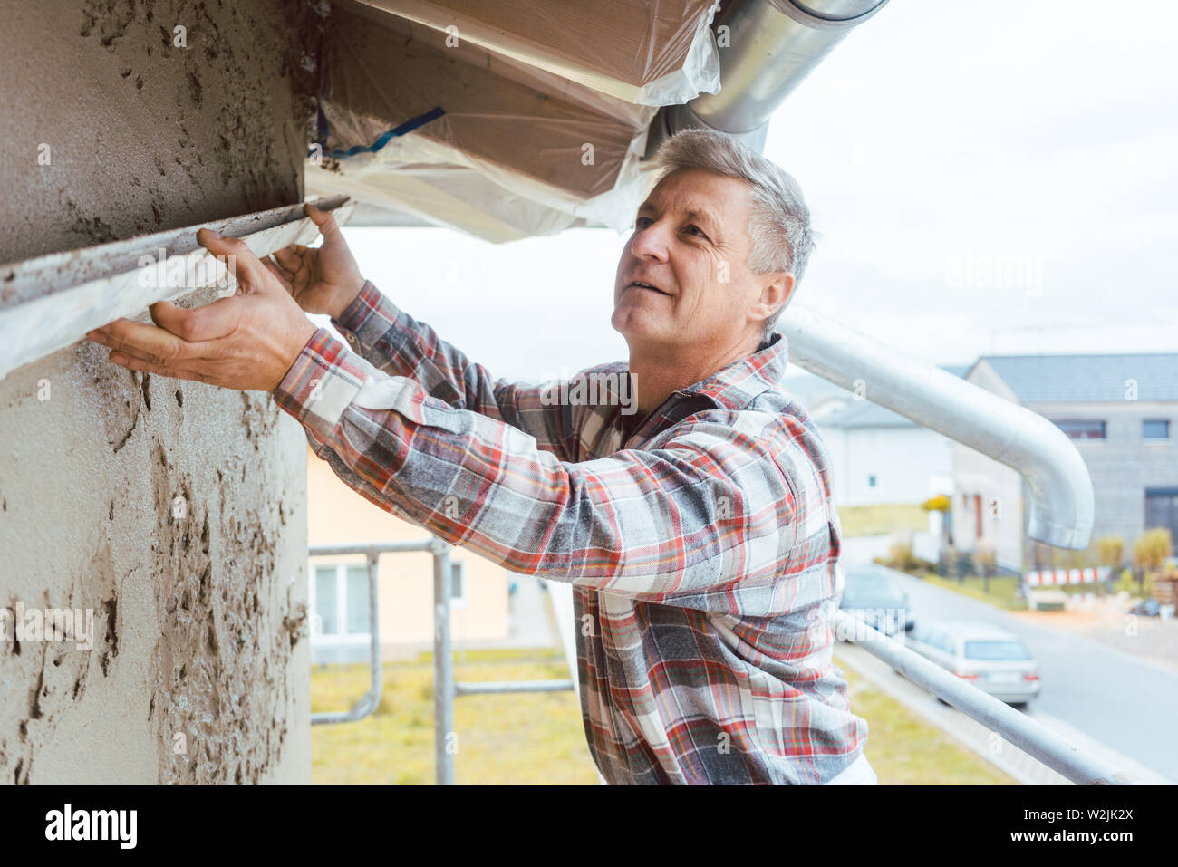 Plasterer smoothing plaster on a facade Stock Photo - Alamy