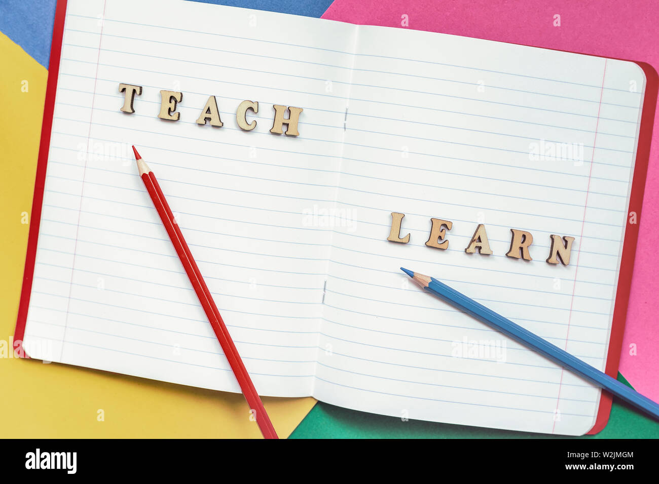 Teach and learn, words an open notebook, colored paper sheets. Concept ...