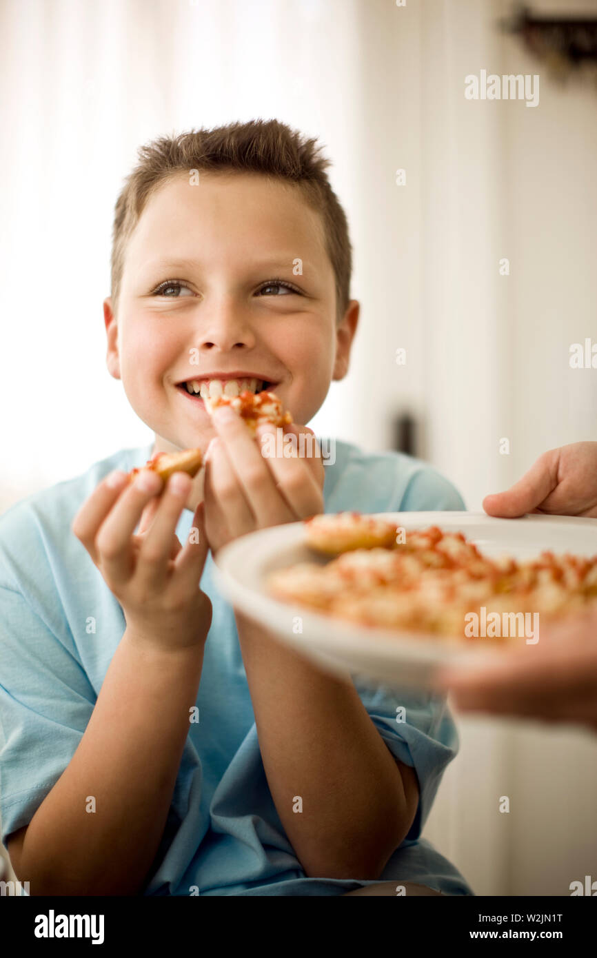 Boy eating food given to him on plate Stock Photo - Alamy