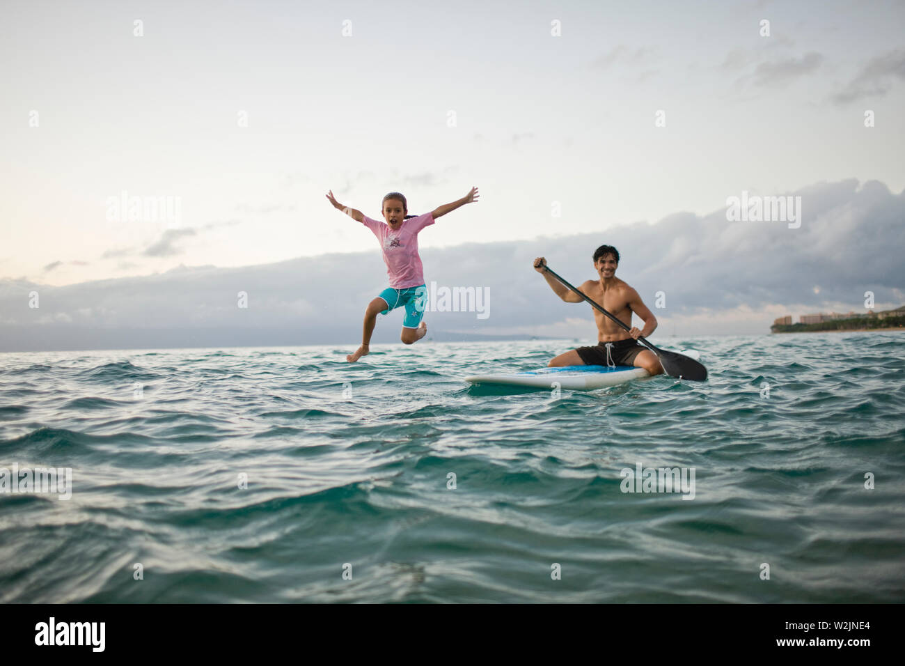 Little girl jumping off paddleboard Stock Photo - Alamy