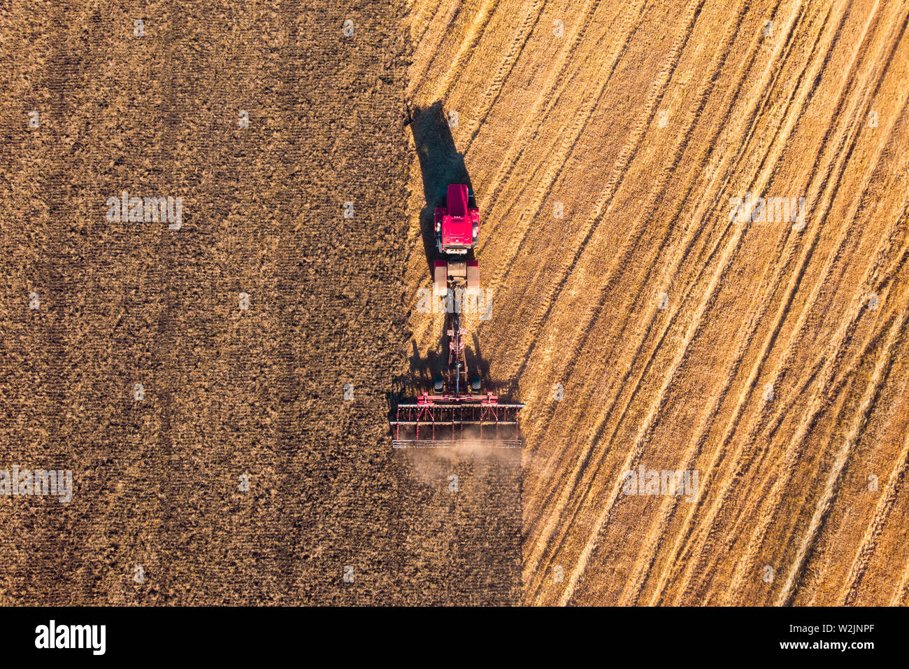 Low altitude aerial top down photo of meadow and farmer in tractor ...