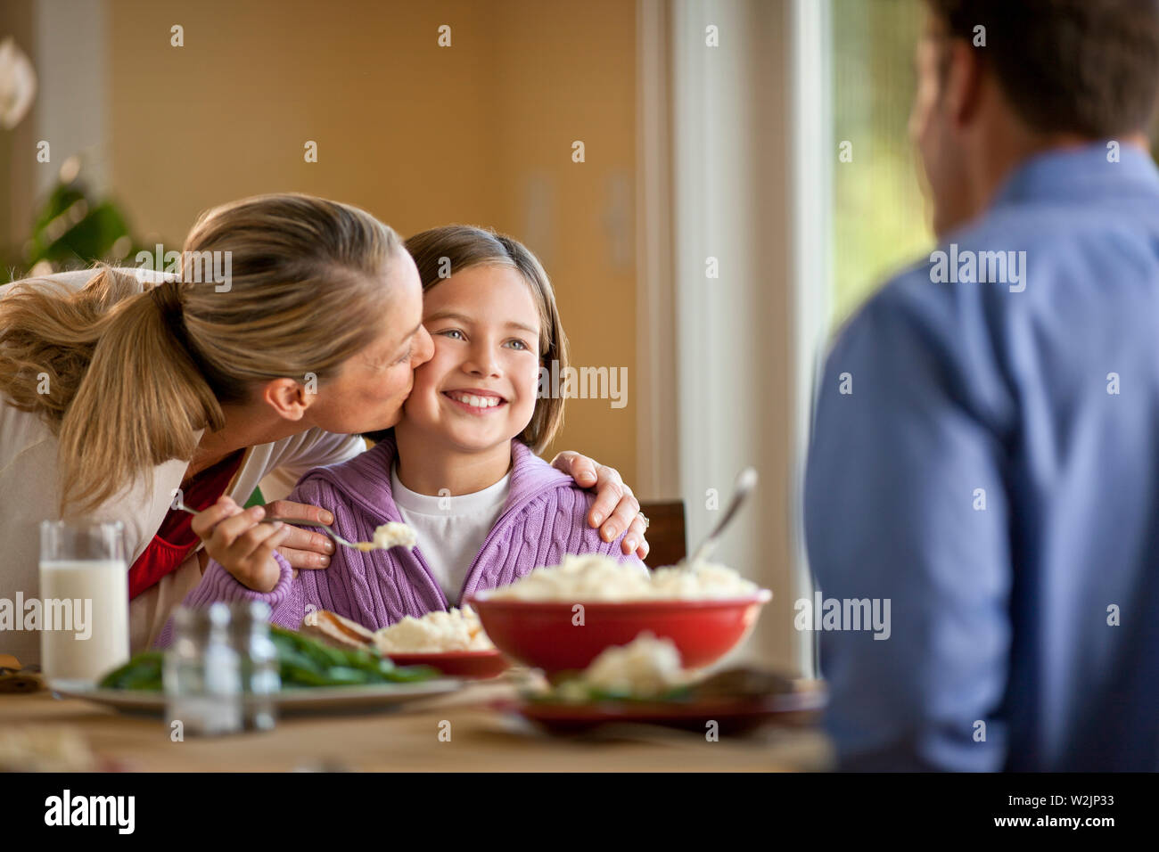 Happy family sharing a meal together around a dining table Stock Photo ...