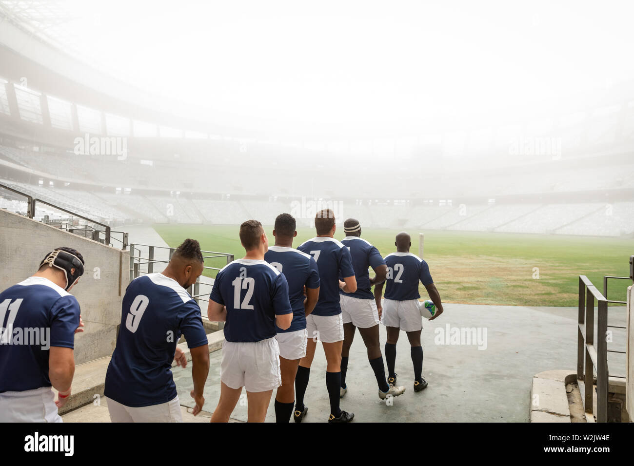 Diverse male rugby players standing at the entrance of stadium in a row ...