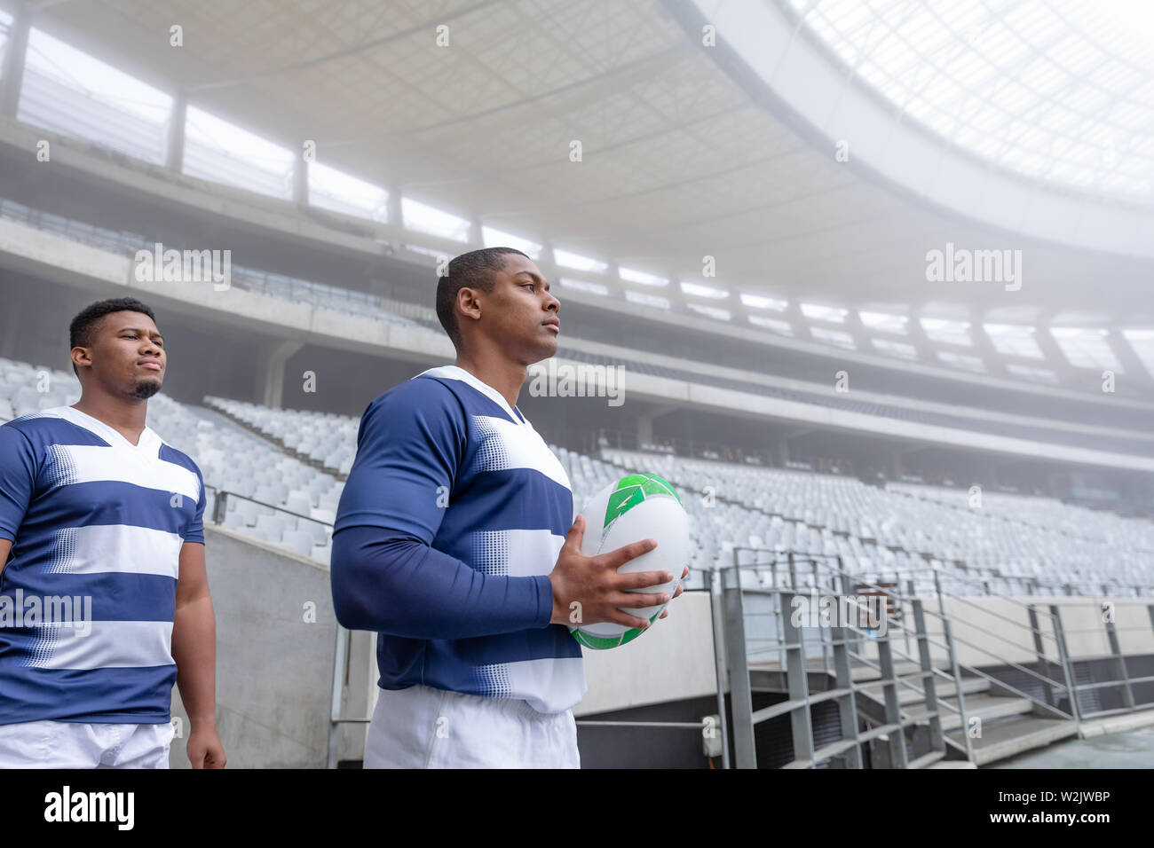Diverse male rugby player standing in a row at the entrance of stadium ...