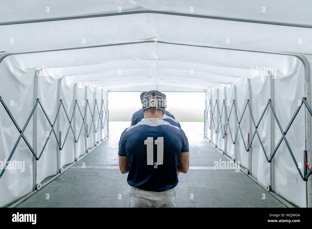 Diverse male rugby players standing together in a row at the entrance ...
