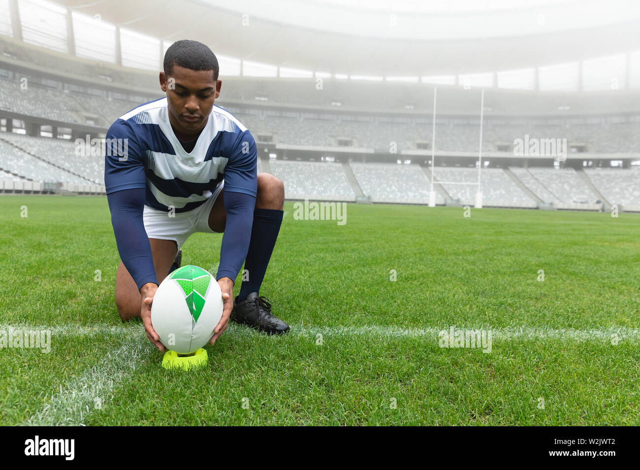 African American male rugby player placing rugby ball on the stand in ...