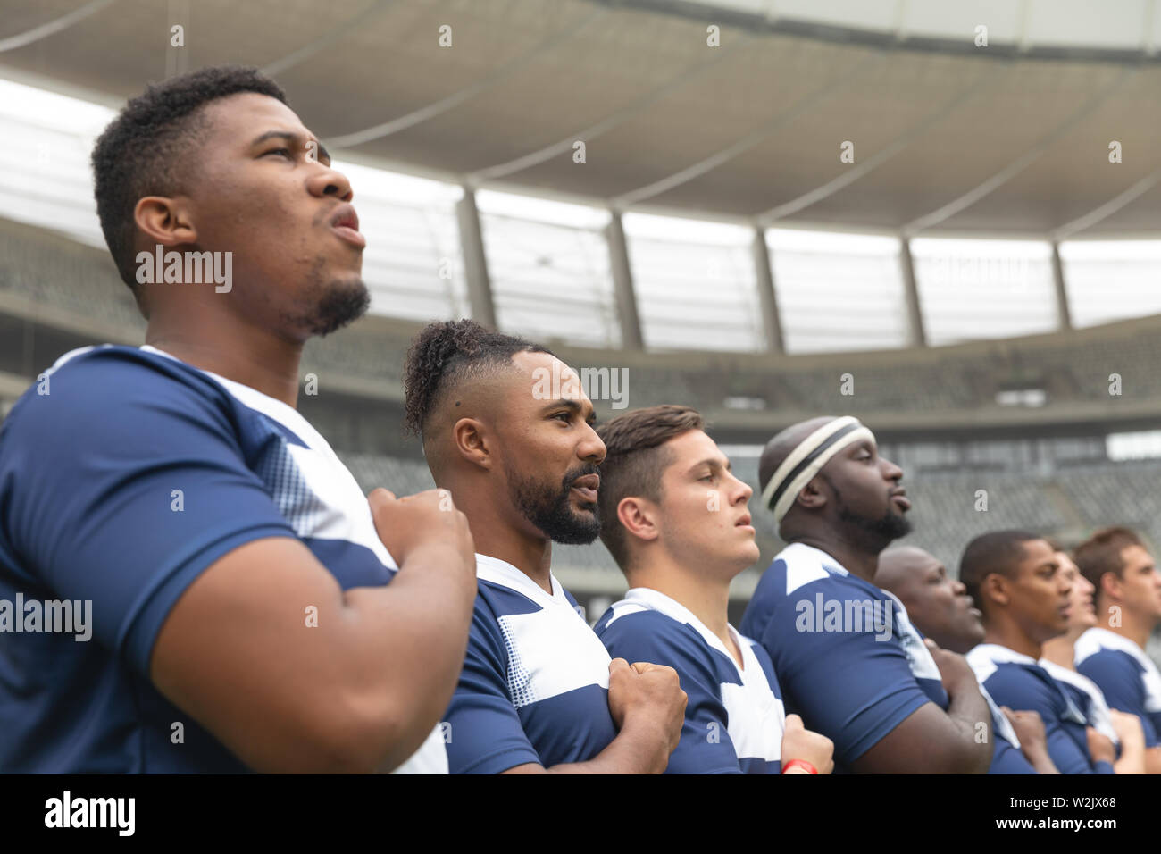 Group of diverse male rugby players taking pledge together in stadium ...