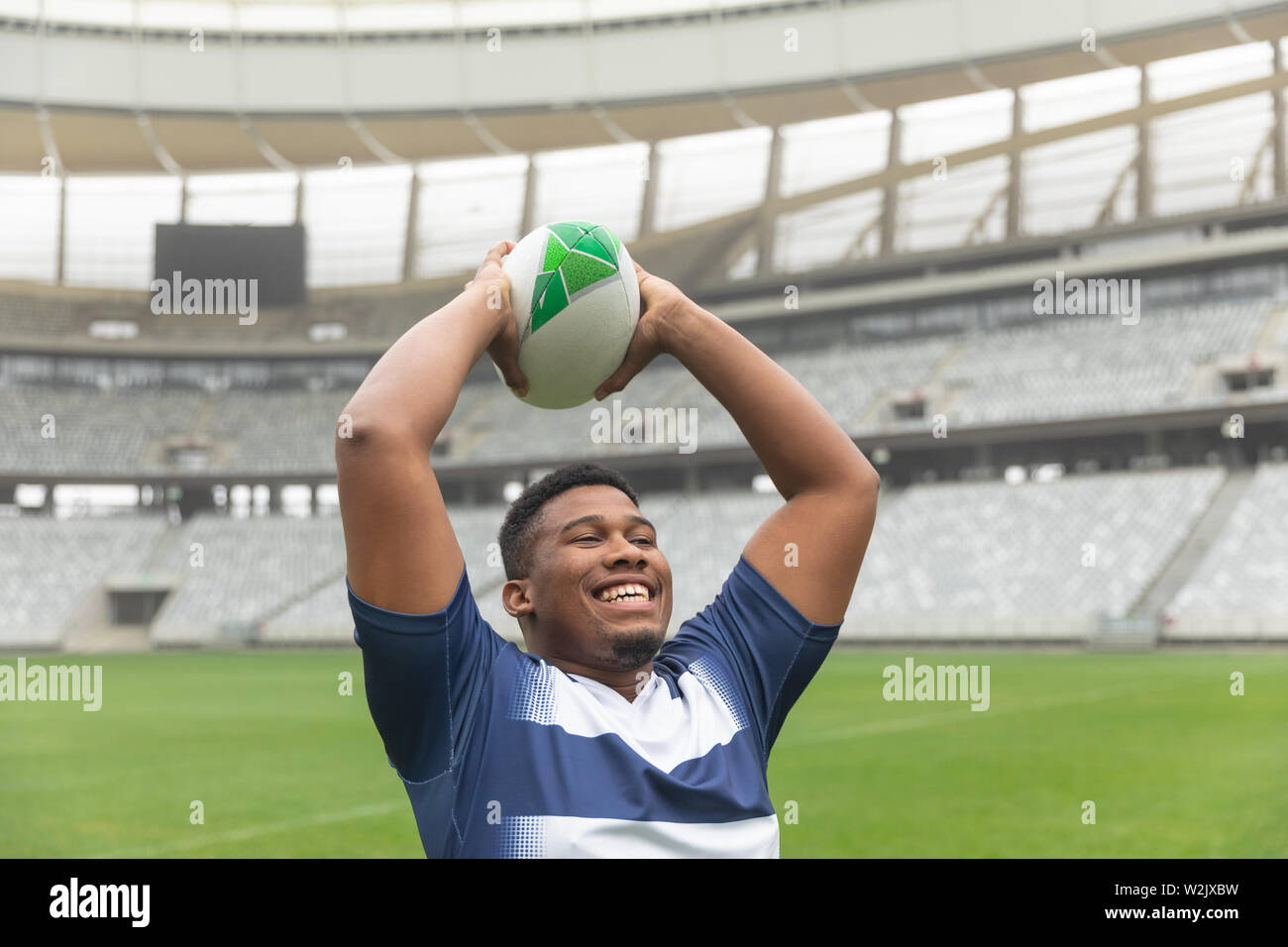 Happy African American Rugby player throwing rugby ball in the stadium ...