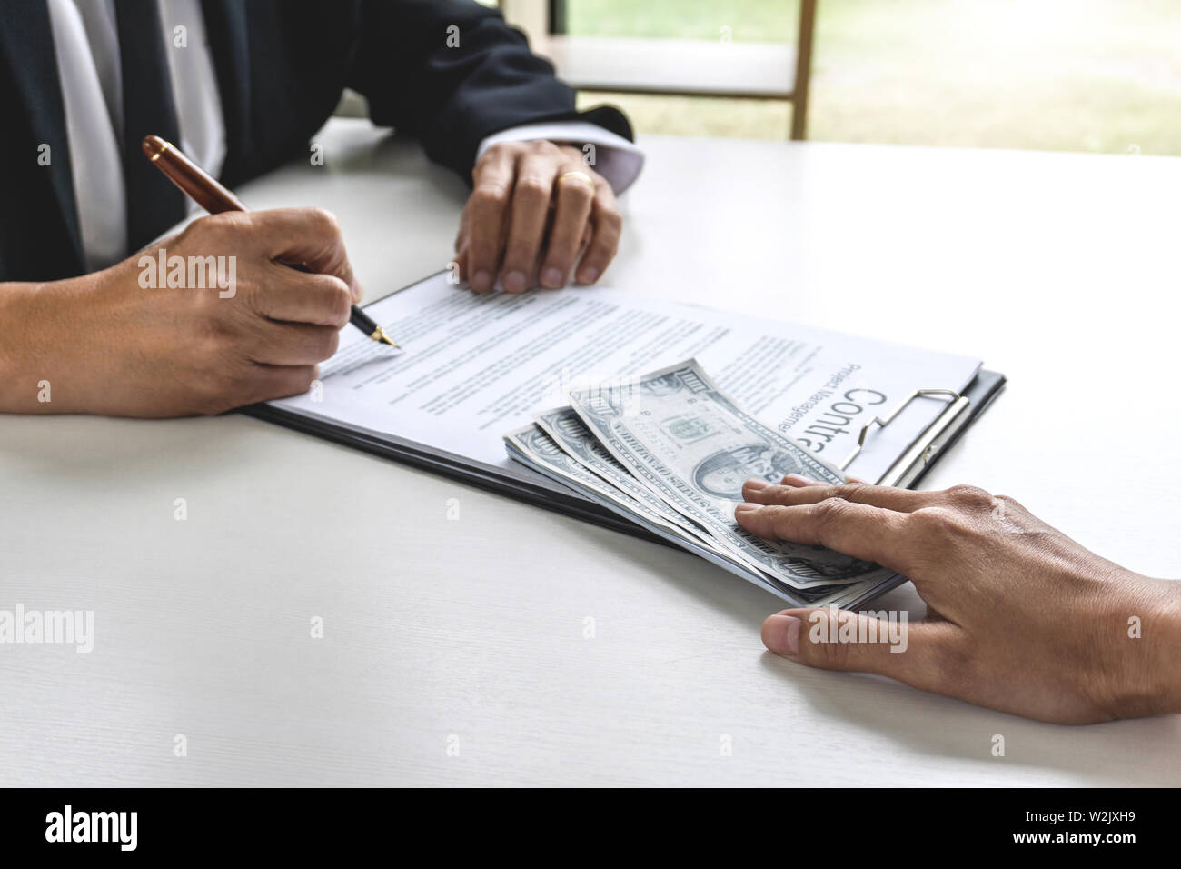Business woman giving bribe money the form of dollar bills to mature ...
