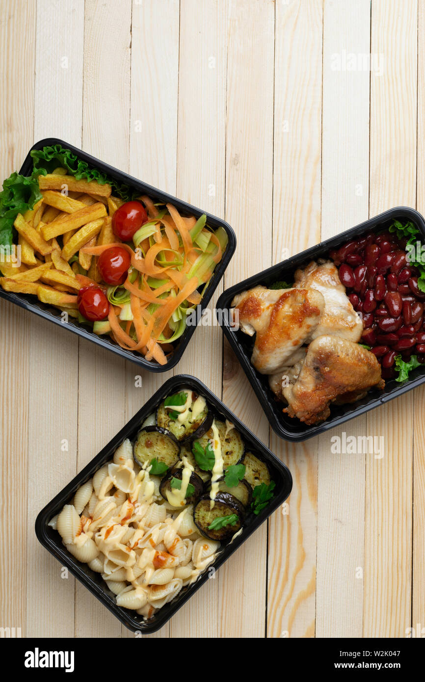 vertical photo of business lunch in food boxes, roast chicken wings ...