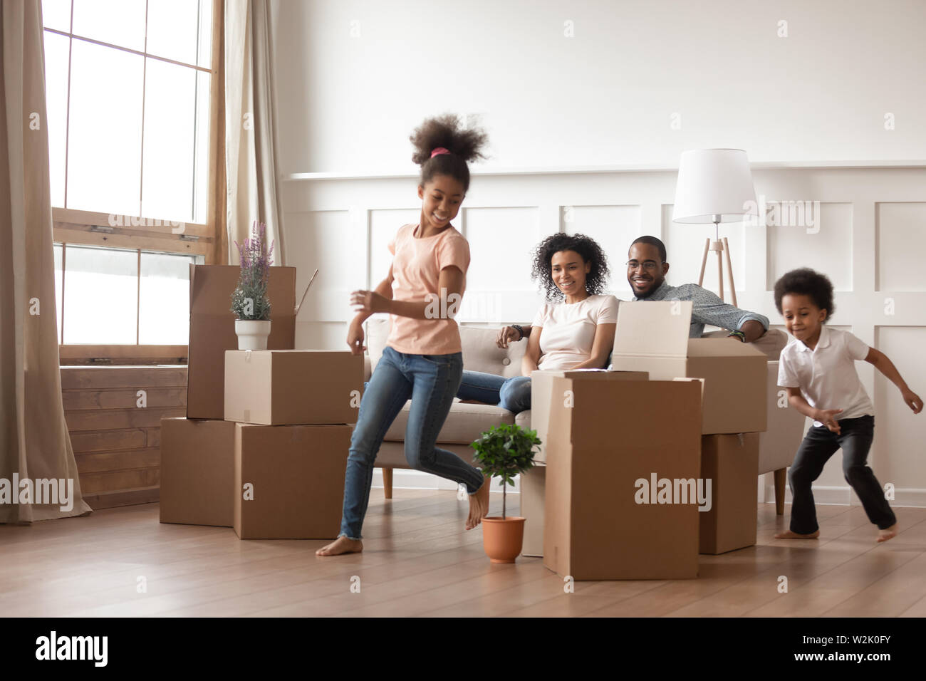 Active african kids running around boxes laughing on moving day Stock ...