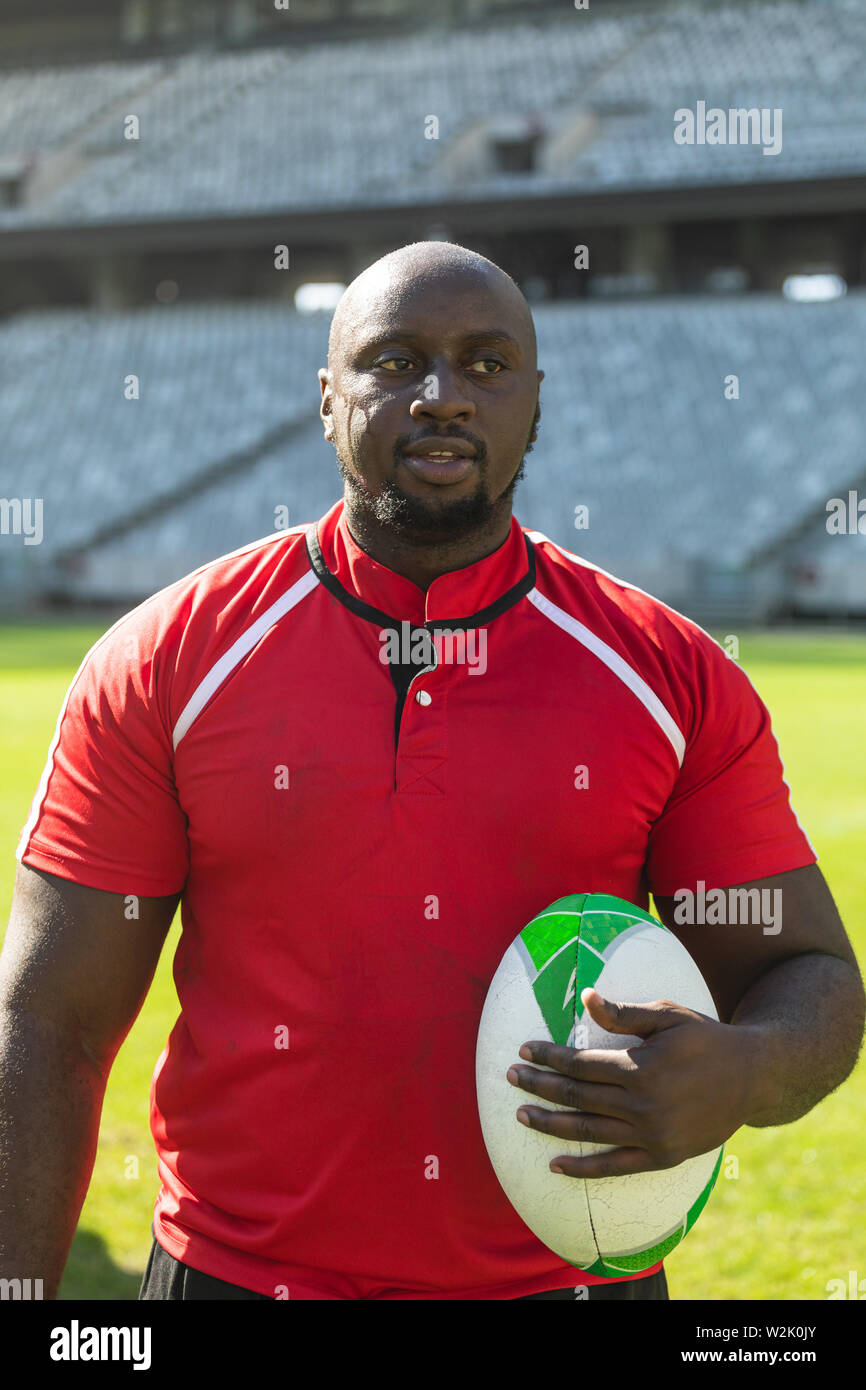 Rugby player standing with rugby ball and looking away in stadium Stock ...
