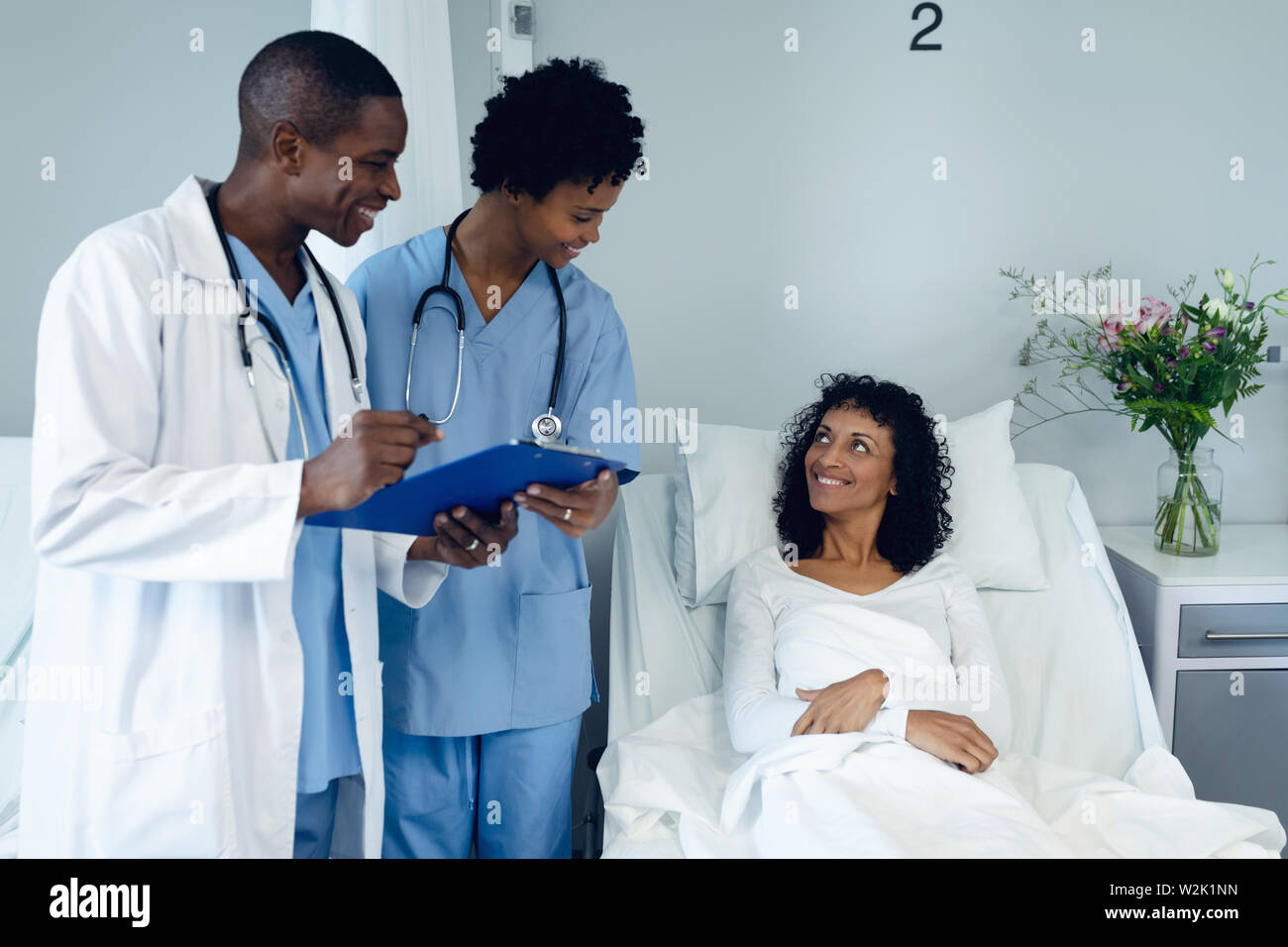 Male and female doctors interacting with female patient in the ward ...