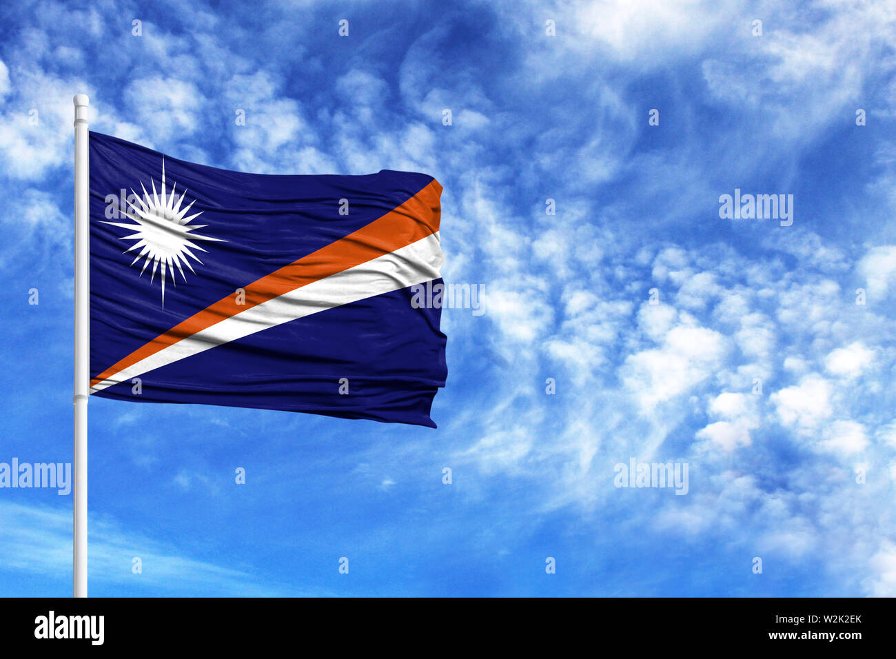 National flag of Marshall Islands on a flagpole in front of blue sky ...