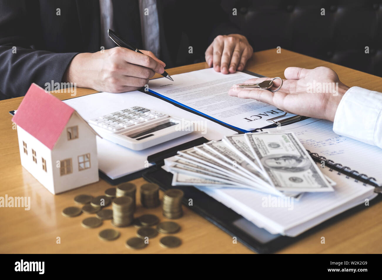 Estate agent giving house keys to client after signing agreement ...