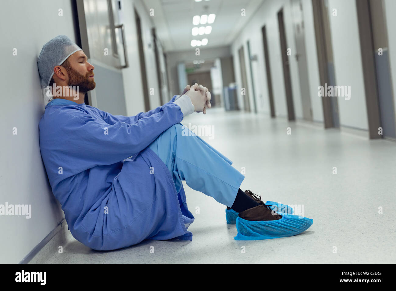Tensed male surgeon sitting in the corridor Stock Photo - Alamy