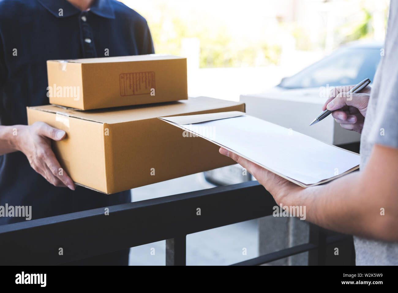 Delivery mail man giving parcel box to recipient, Young man signing ...