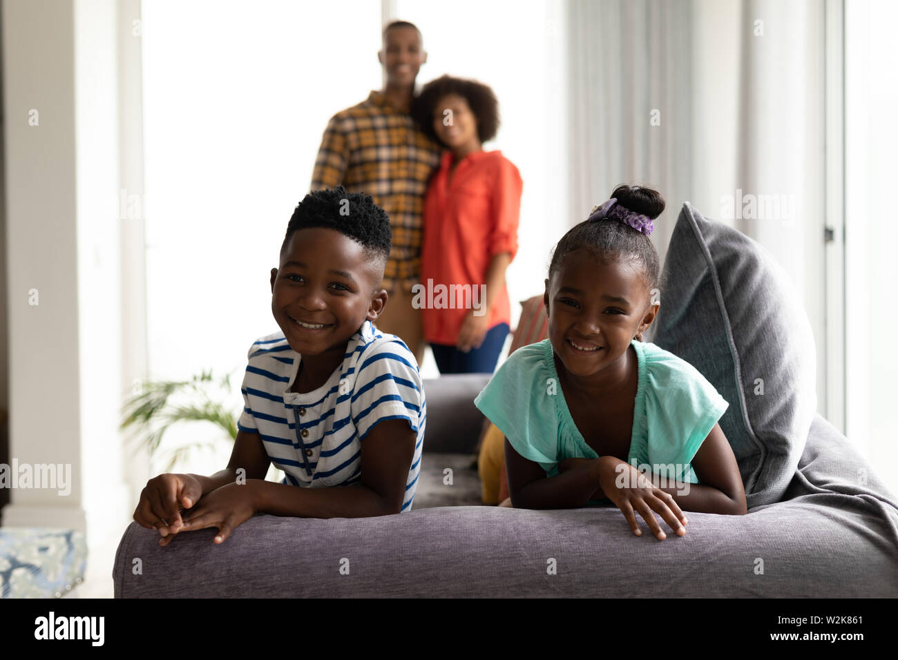 Children sitting on a sofa while their parents standing in the ...