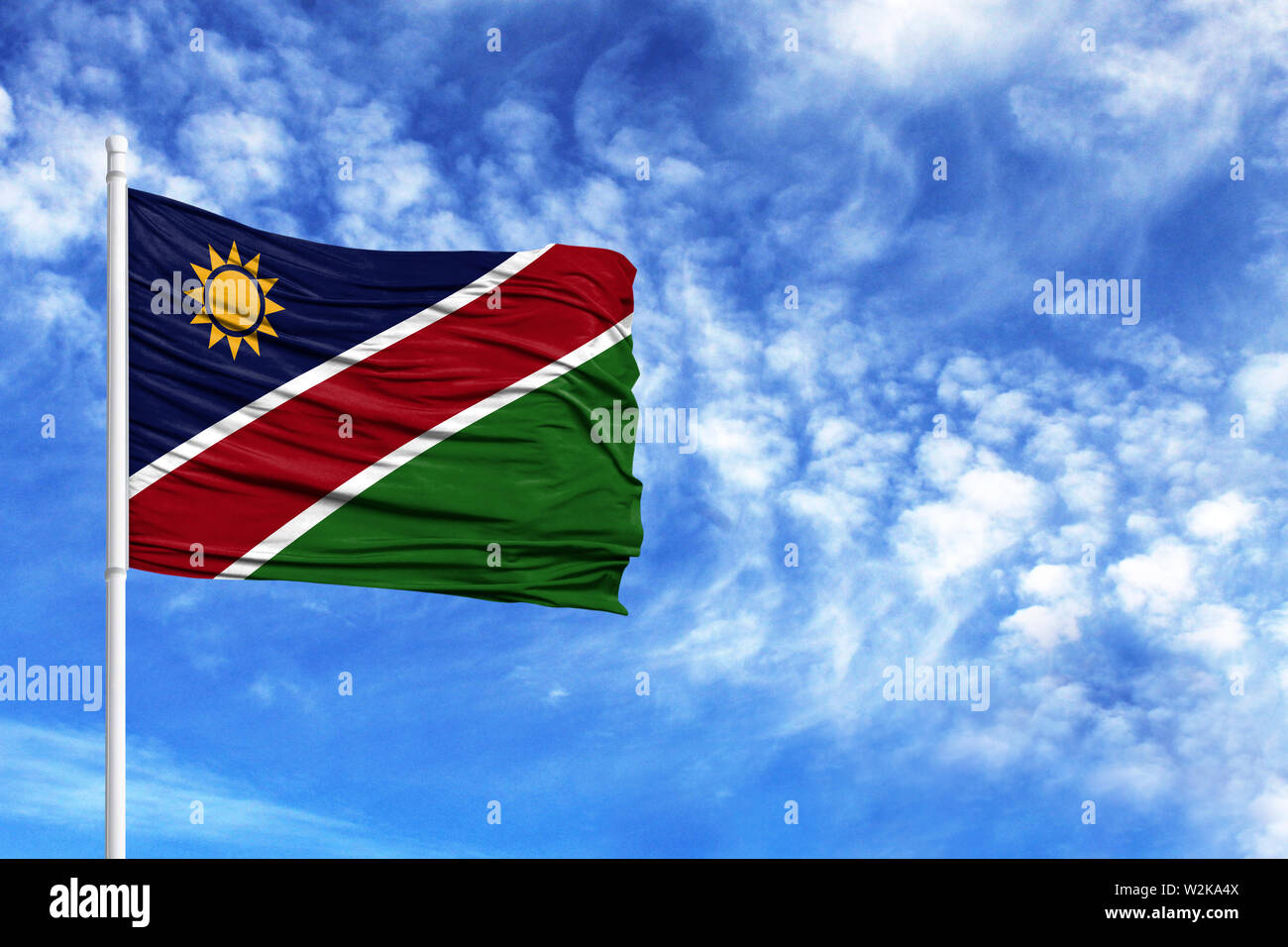 National flag of Namibia on a flagpole in front of blue sky Stock Photo ...