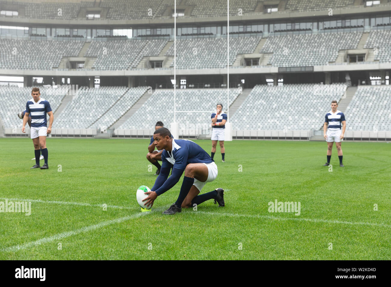 African American Male rugby player placing rugby ball on a stand in ...