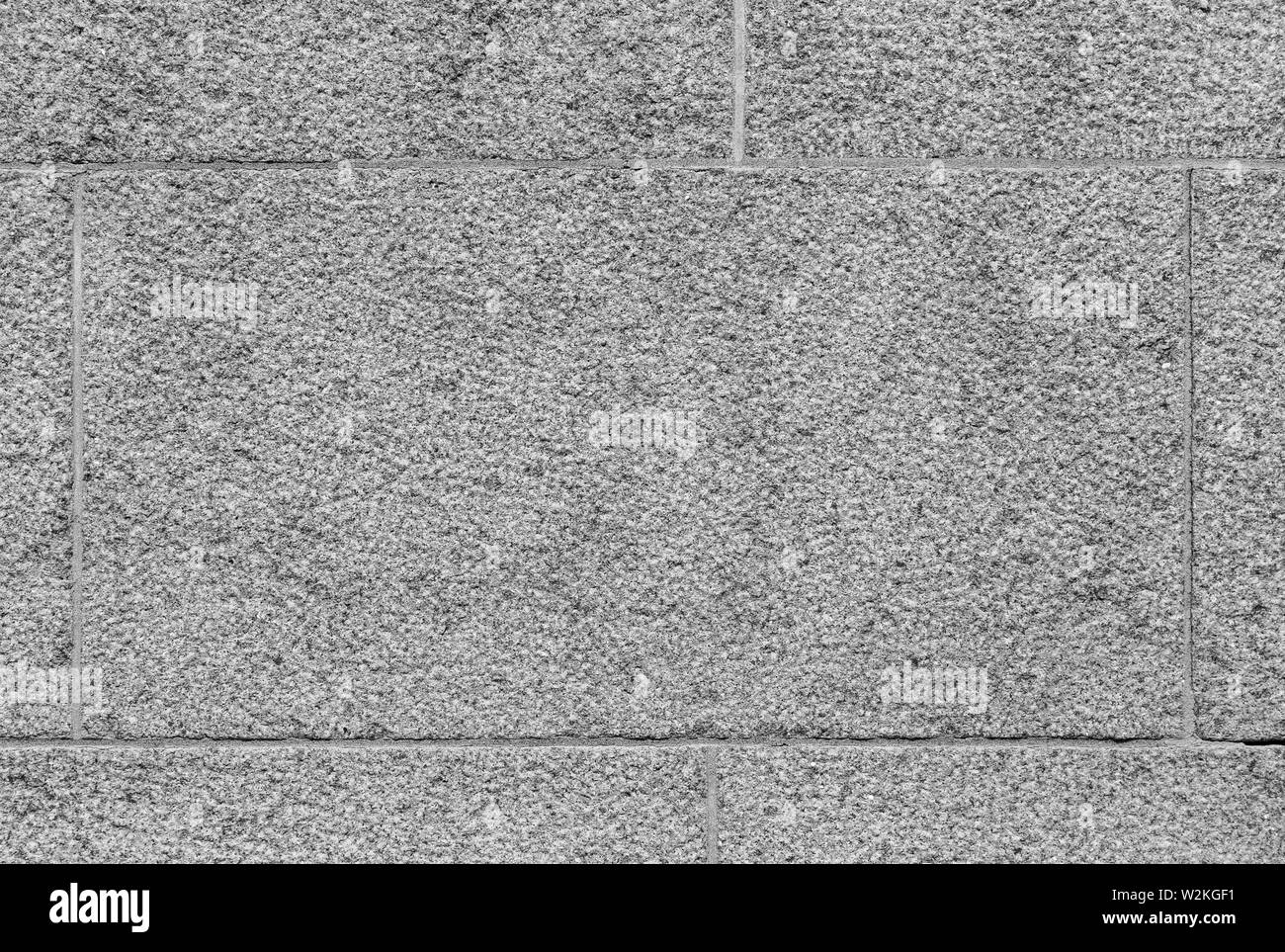 Close-up of part of a bumpy granite block stone wall in black and white ...