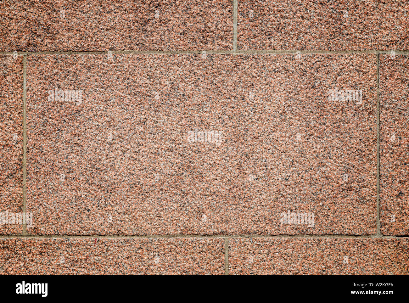 Close-up of part of a bumpy red granite block stone wall with vignette ...