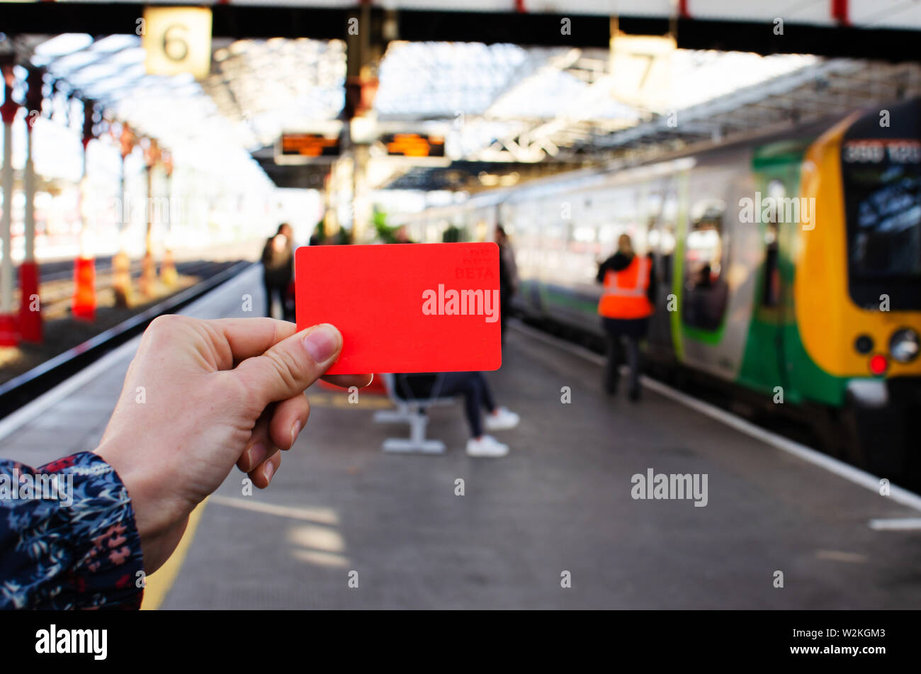 Empty coral (red) plastic card in a girl's hand. The blurred background ...