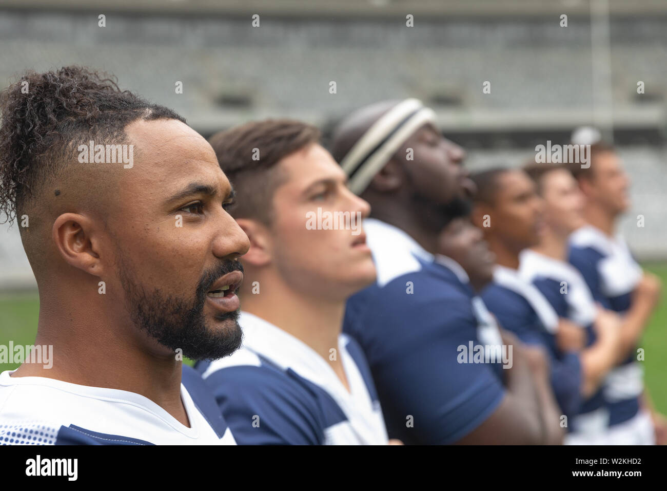 Group of diverse male rugby players taking pledge together in stadium ...