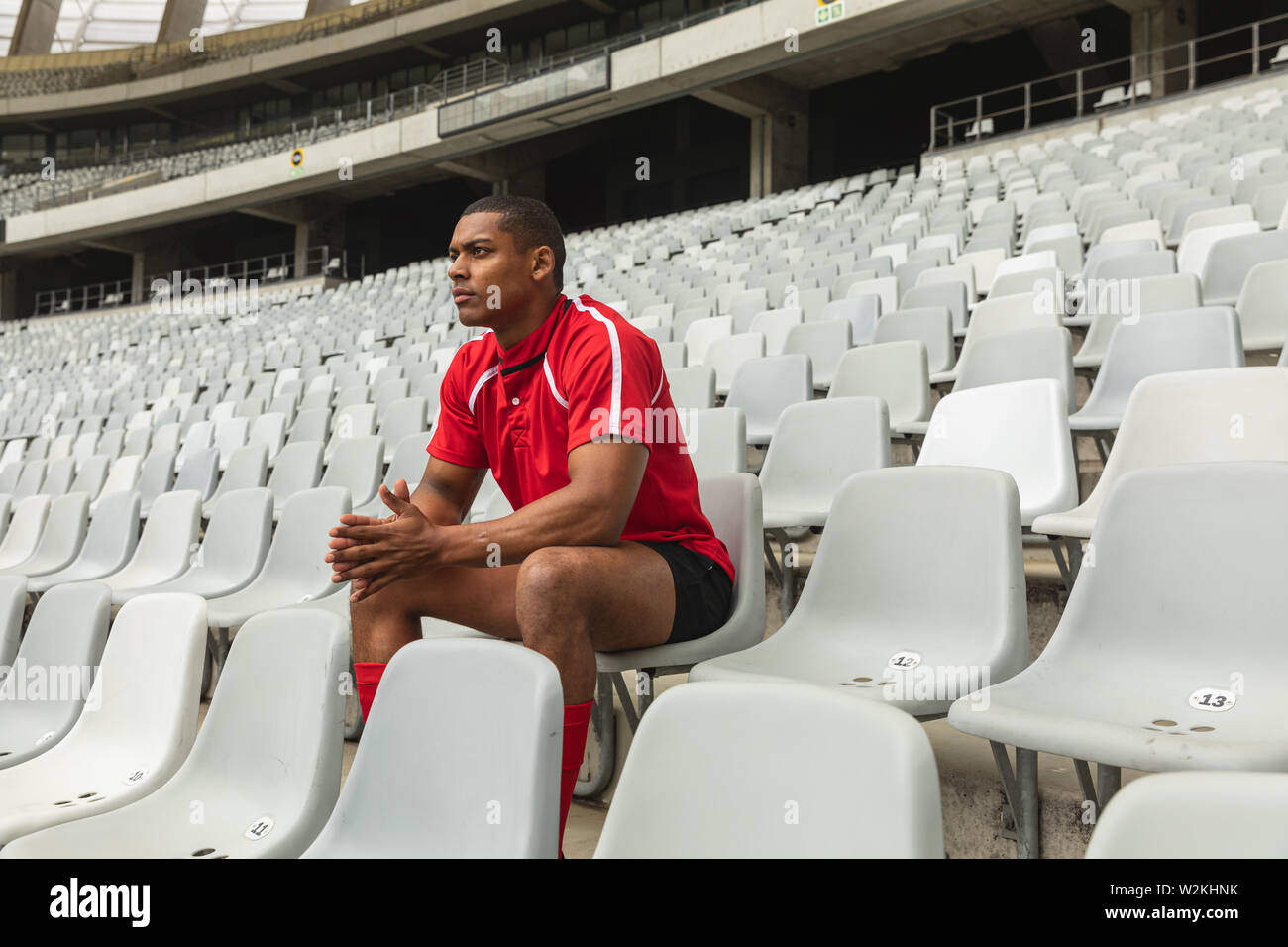 Thoughtful male rugby player sitting alone in stadium Stock Photo - Alamy