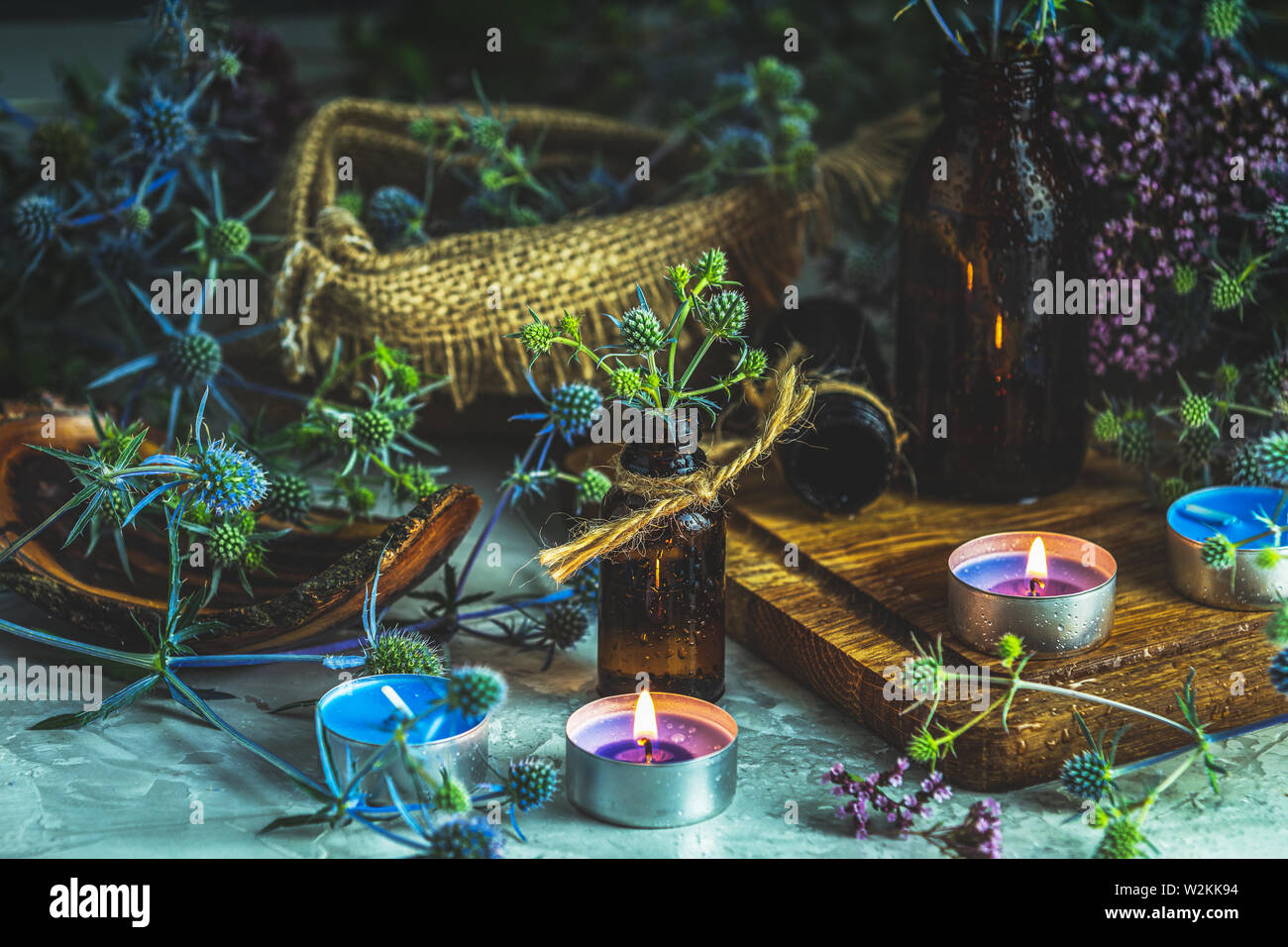 Magic potion in small bottle, blue eryngo and candles on dark ...