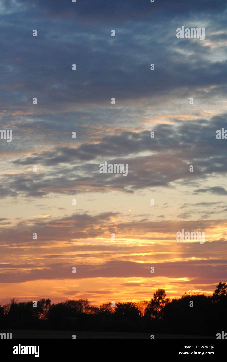 A colourful sunset with golden sky and dark blue, indigo clouds Stock ...