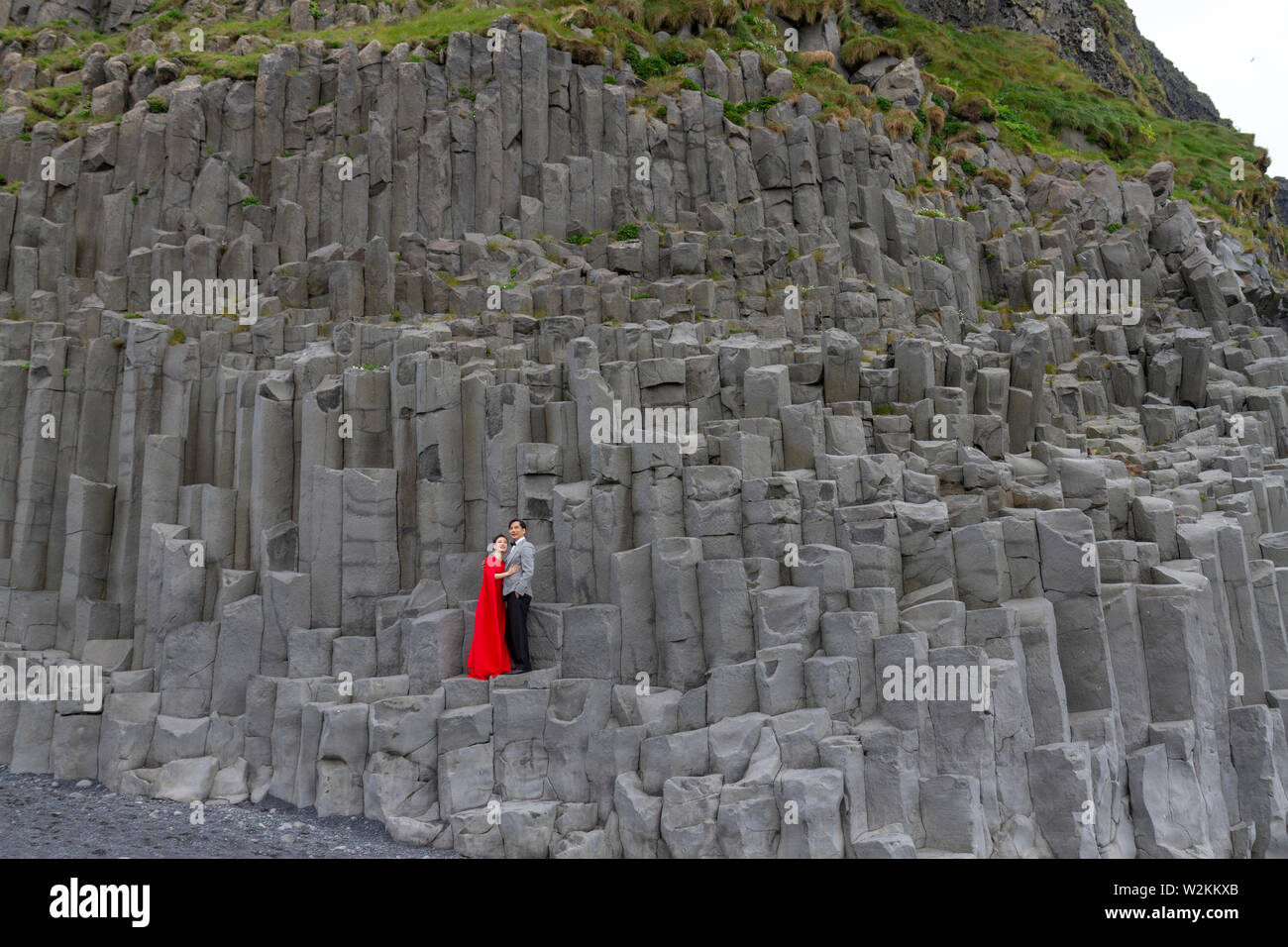 A wedding couple having photos taken on basalt columns on Reynisfjara ...