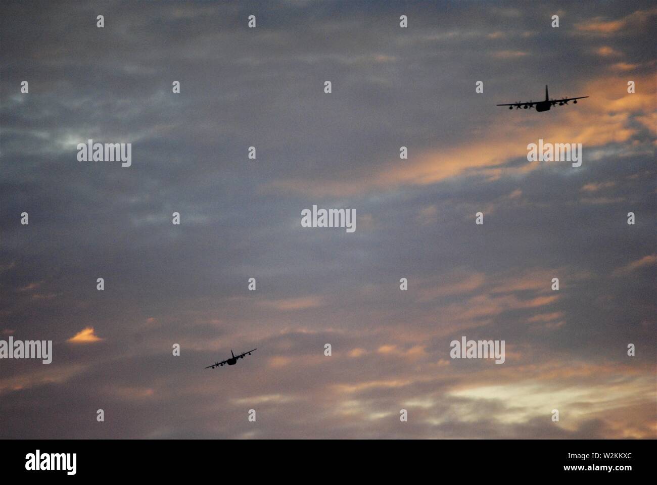 A pair of C 130 Hercules transport aircraft flying in to sun set clouds ...