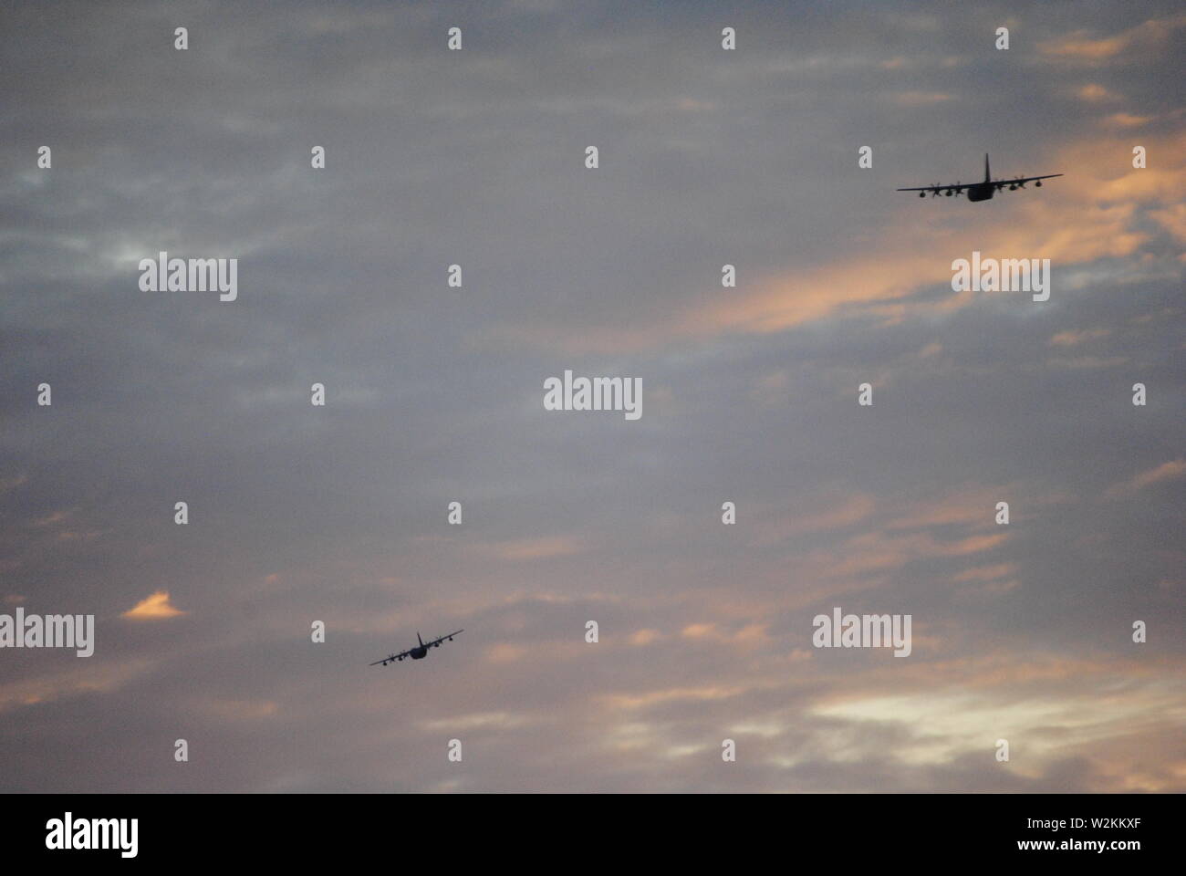 A pair of C 130 Hercules transport aircraft flying in to sun set clouds ...