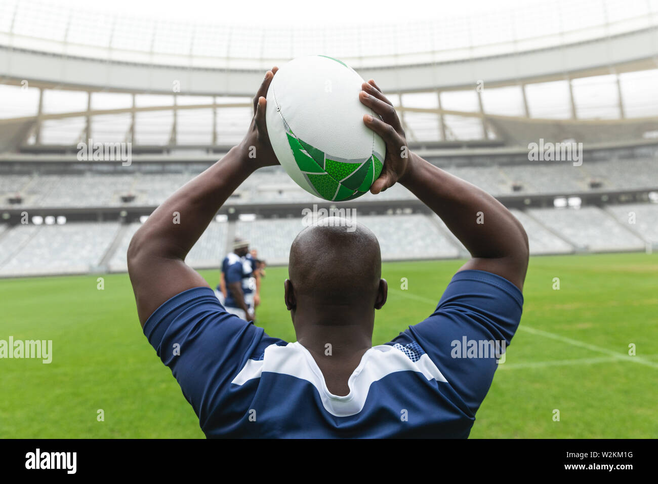 African American male rugby player throwing rugby ball in stadium Stock ...