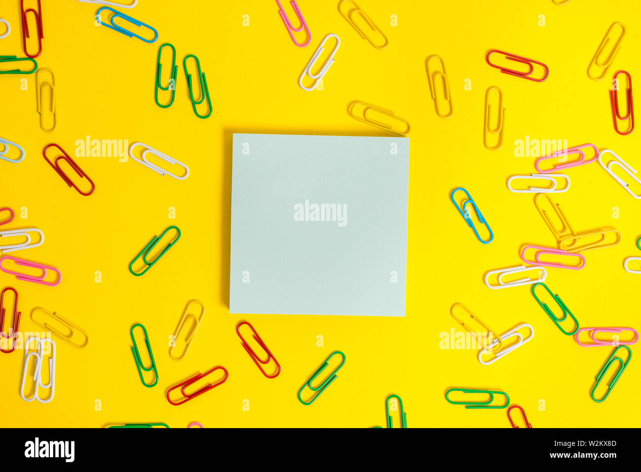 Flat lay above empty paper with copy space and colored paper clips ...