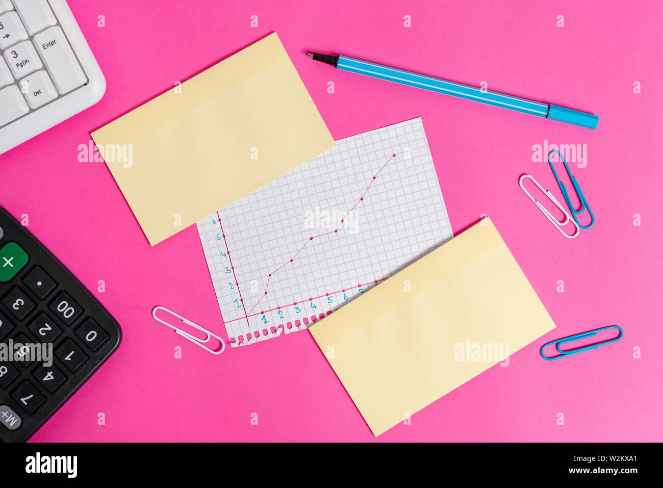 Writing equipments and computer stuffs placed above colored plain table ...