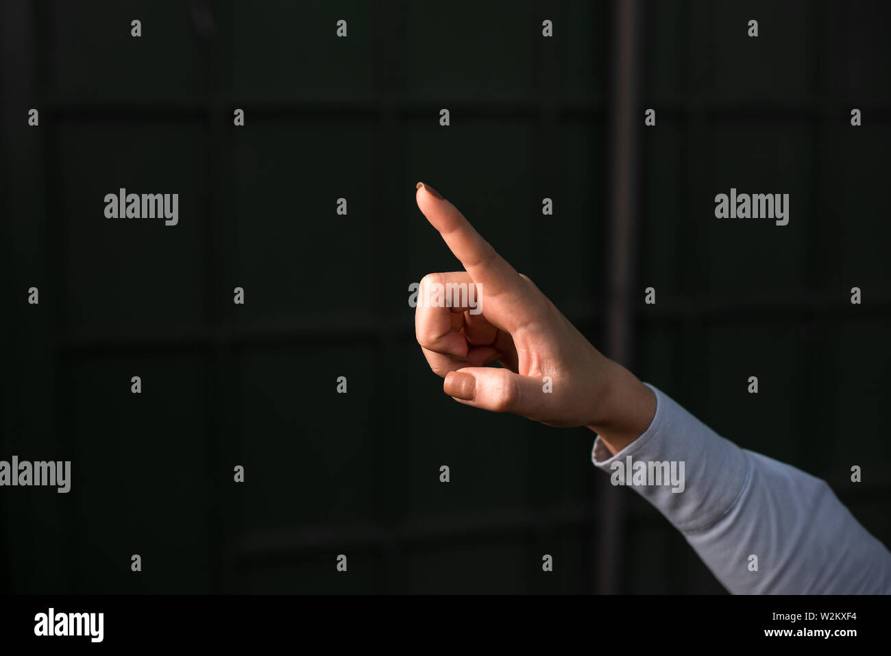 Finger pointing in the empty space. Dark background with hand pointing ...