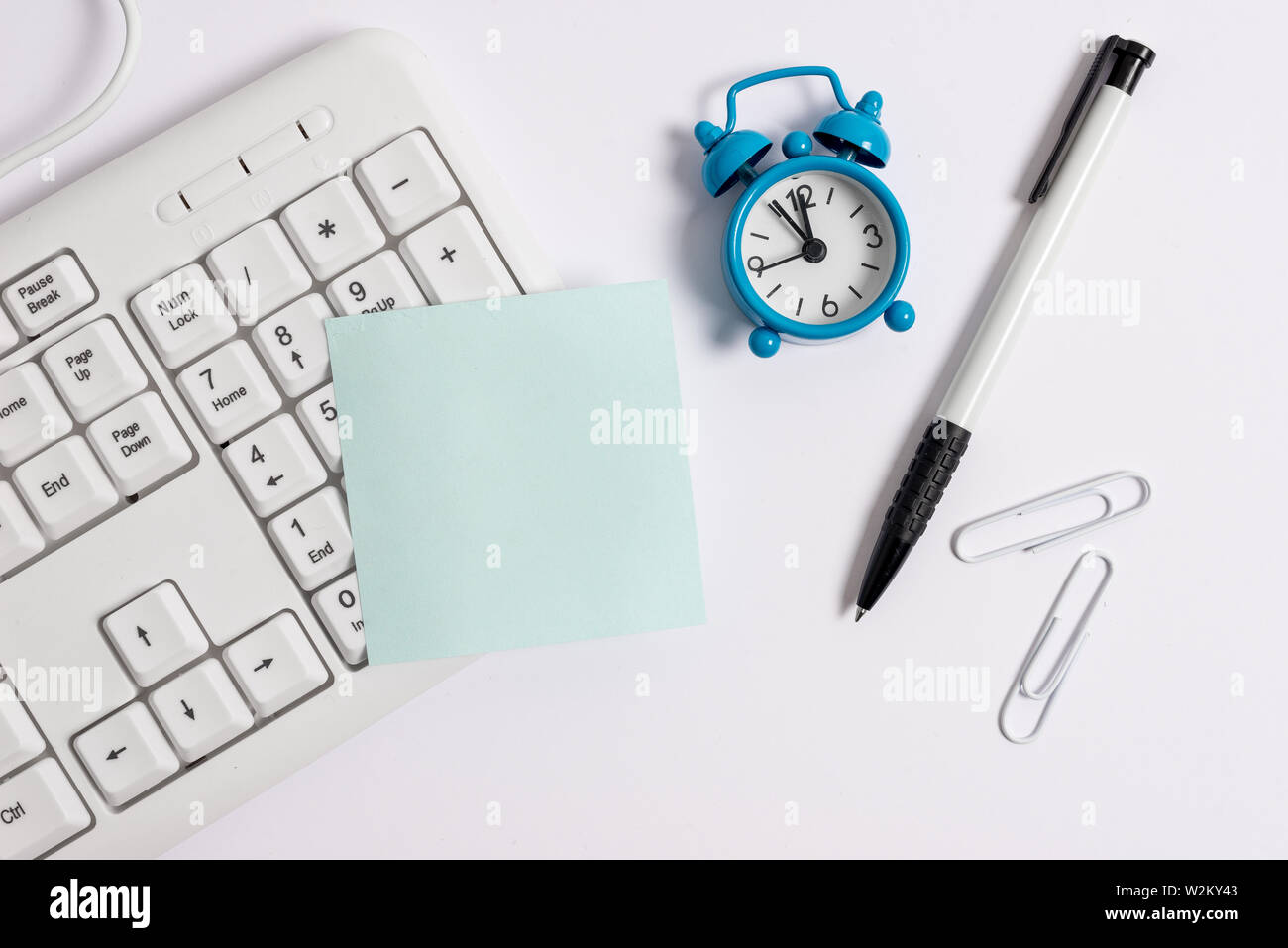 White pc keyboard with empty note paper above white background ...