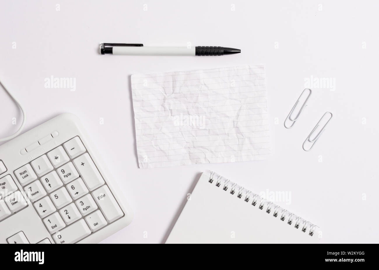 White pc keyboard with empty note paper and pencil above white ...