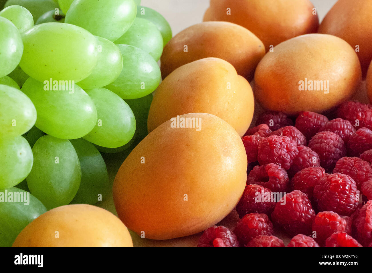 Fresh green grape, raspberry and ripe apricots on top of wooden ...