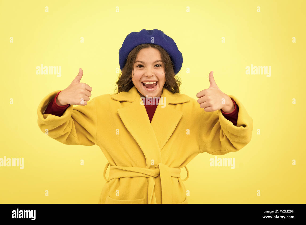 Child promoting something yellow background. Girl show thumbs up ...
