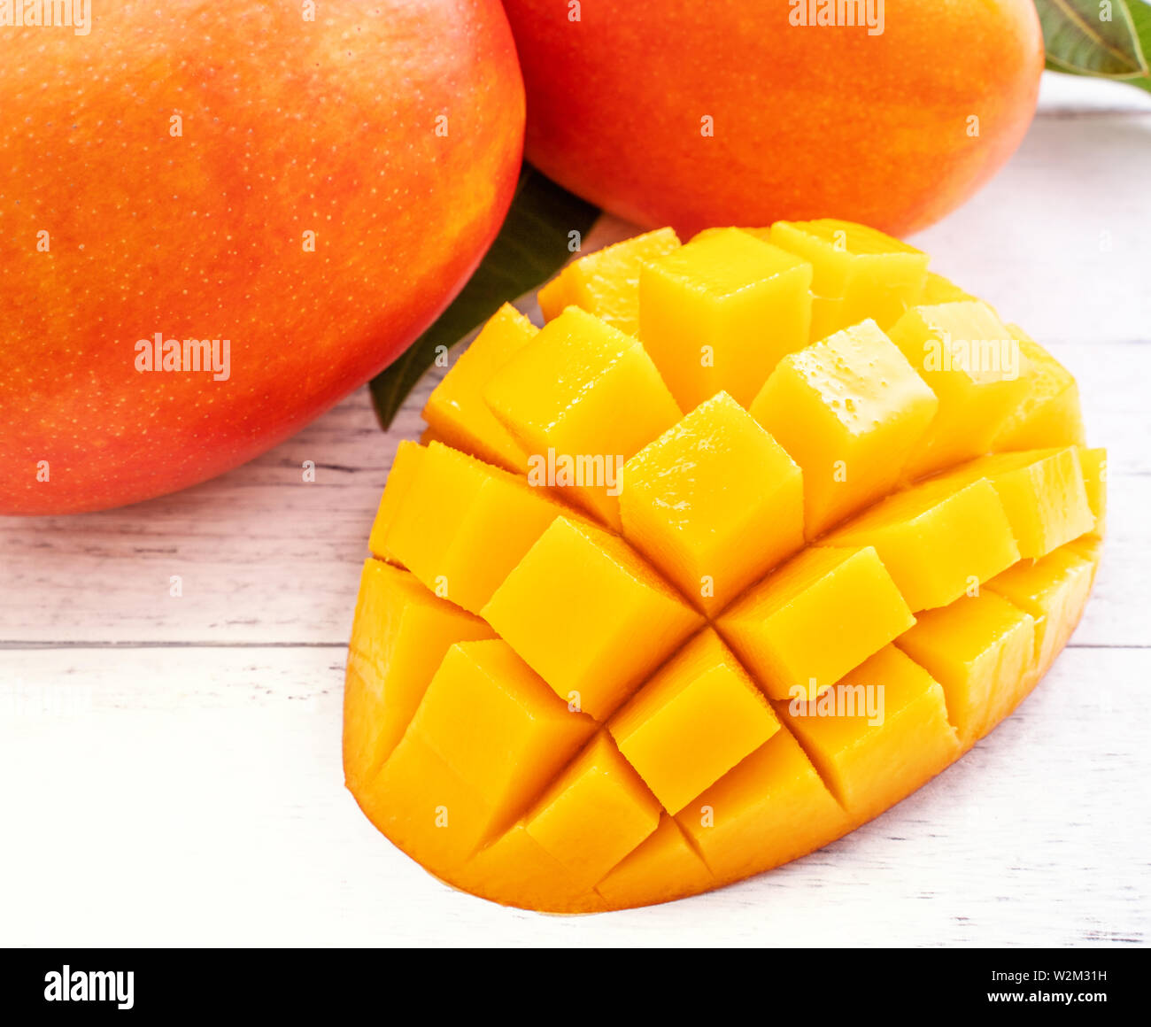 Beautiful chopped mango with green leaves on bright white color timber ...